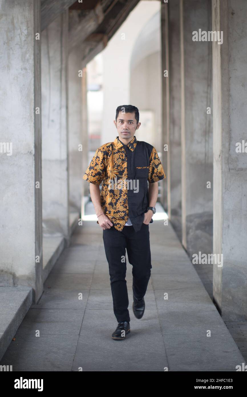 A young male model dressed in Indonesian Batik is posing among rows of ...