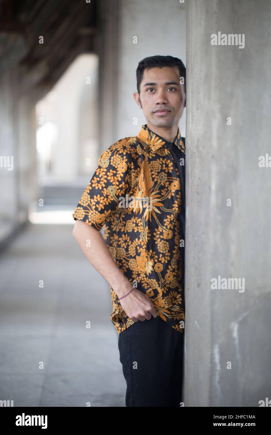 A young male model dressed in Indonesian Batik is posing among rows of ...