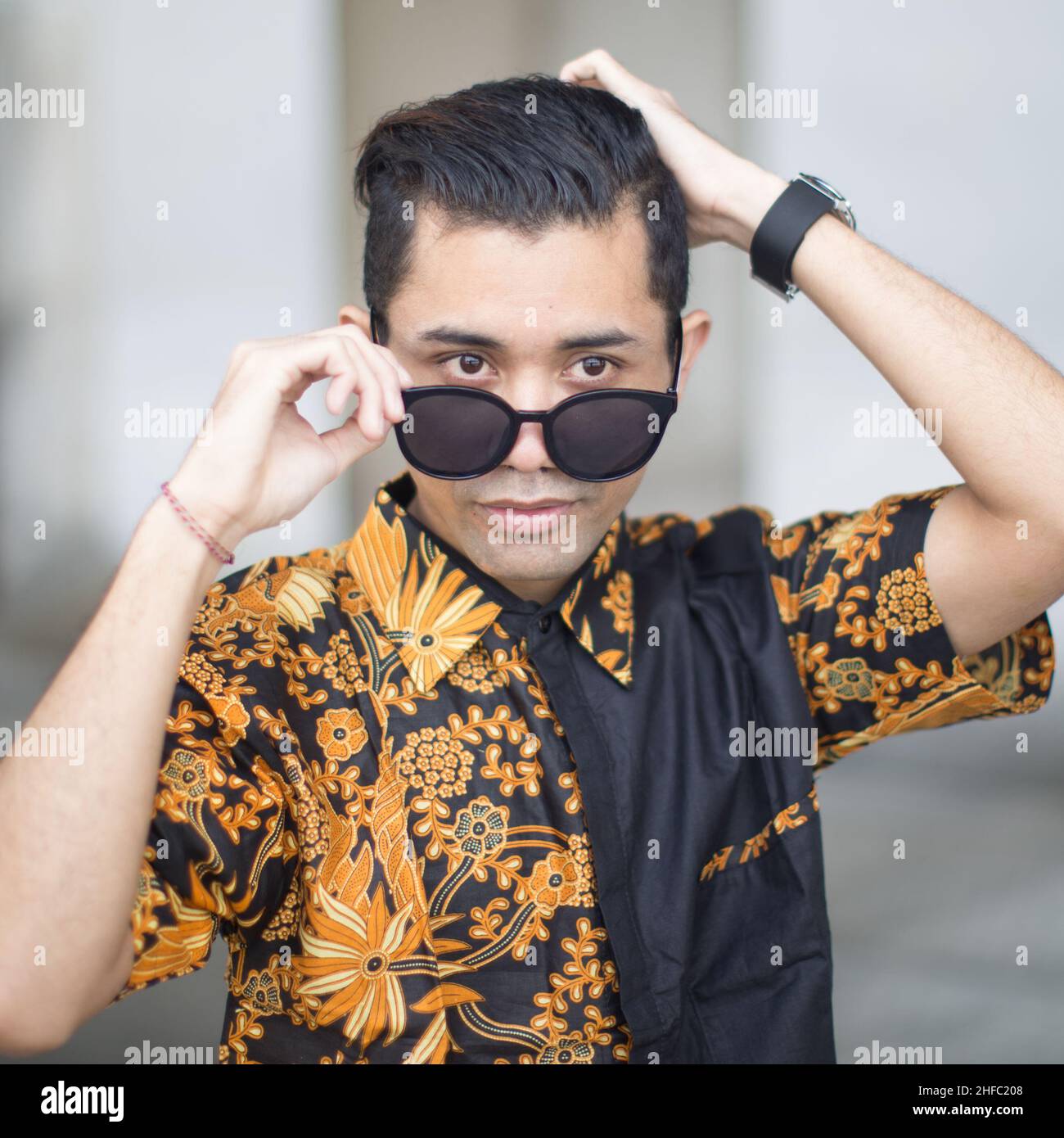 A young male model dressed in Indonesian Batik wears and holds ...