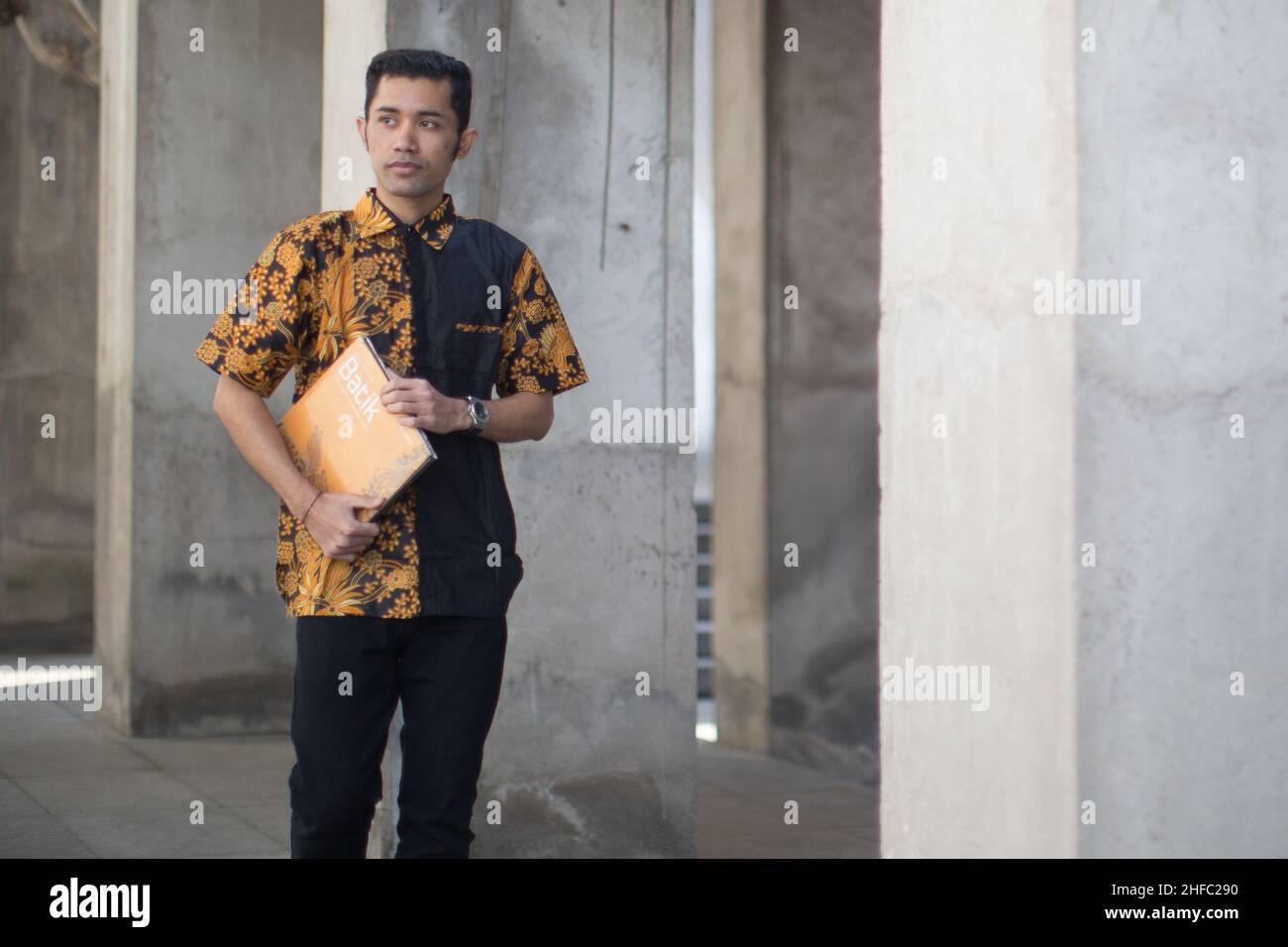 A young male model dressed in Indonesian Batik is walking while holding ...