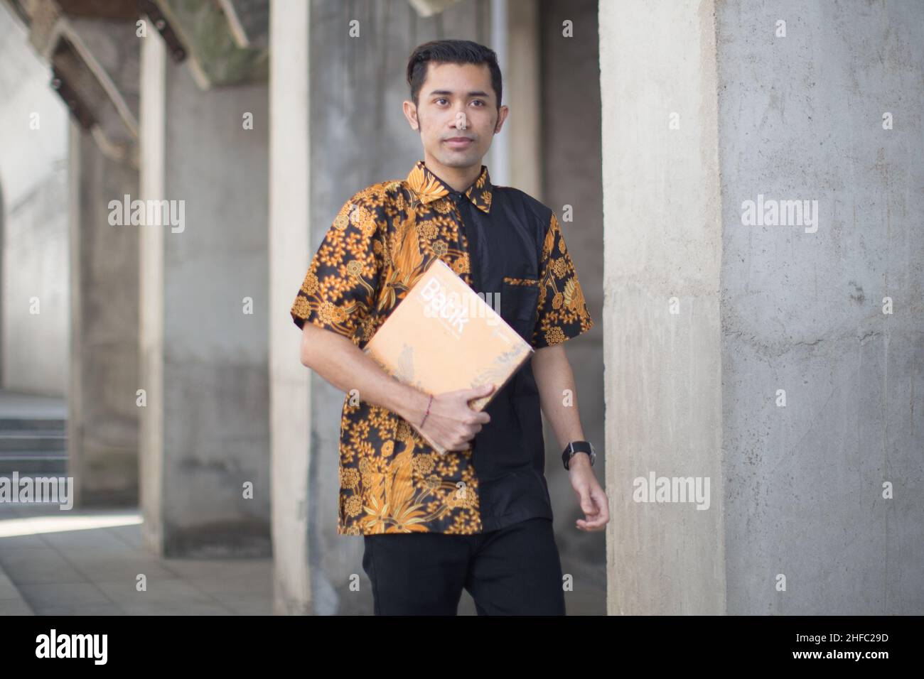 A young male model dressed in Indonesian Batik is walking while holding ...