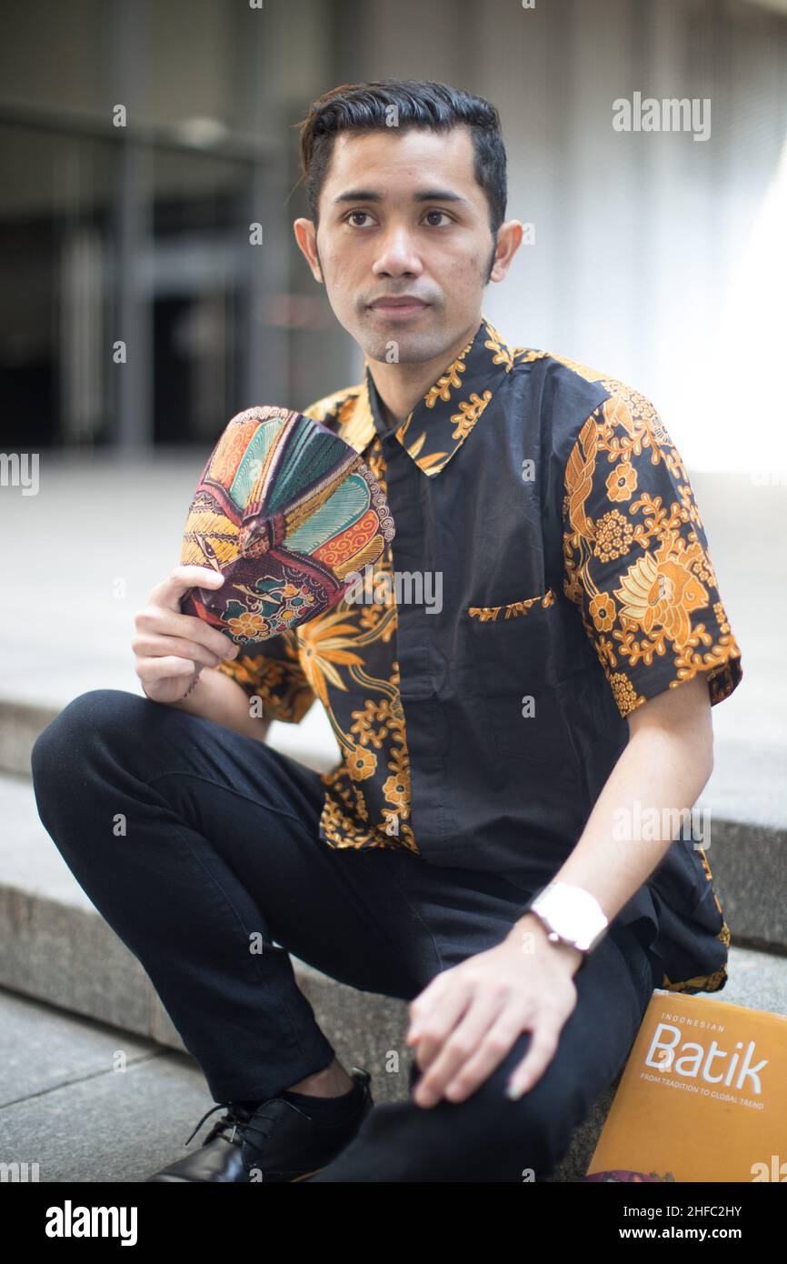 A young male model dressed in Indonesian Batik sits holding a Javanese ...