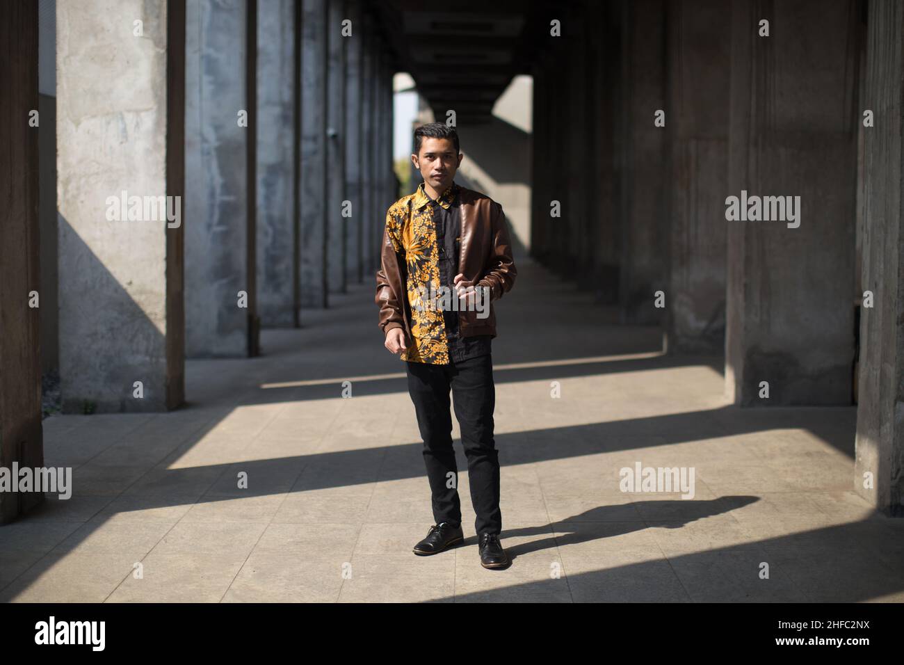 A young male model dressed in Indonesian Batik is posing among rows of ...
