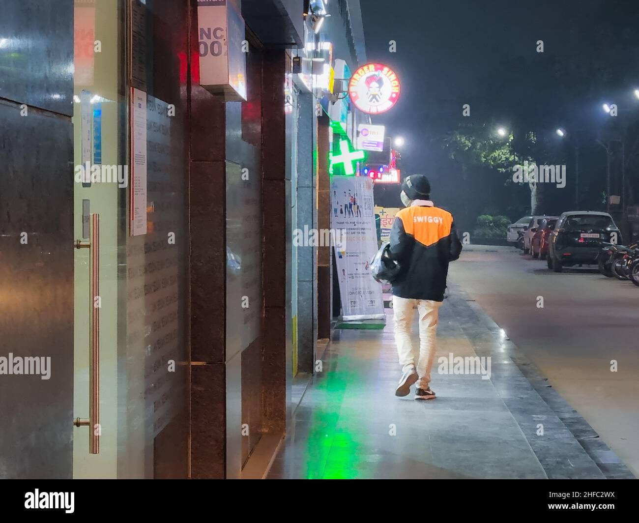 Light night shot of swiggy rider delivery boy walking in a deserted ...