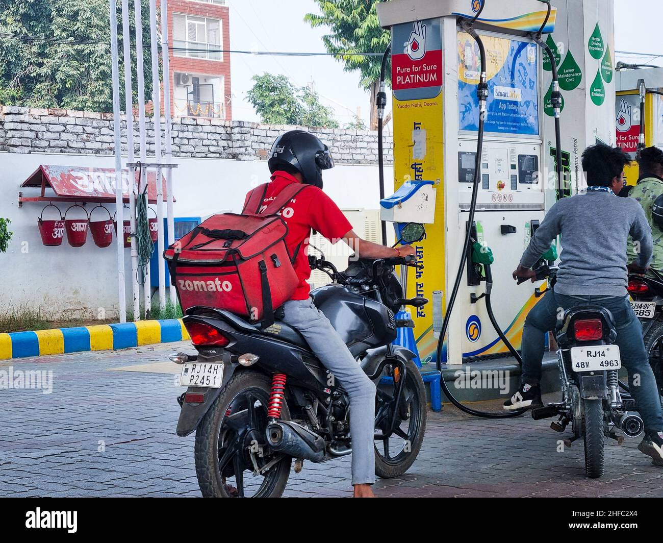 Zomato delivery guy rider waiting at a petrol pump to fill motorcycle ...