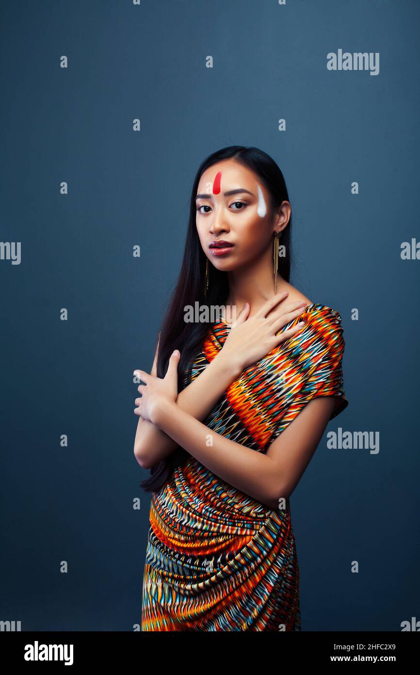 young pretty south asian girl posing in studio on grey background ...
