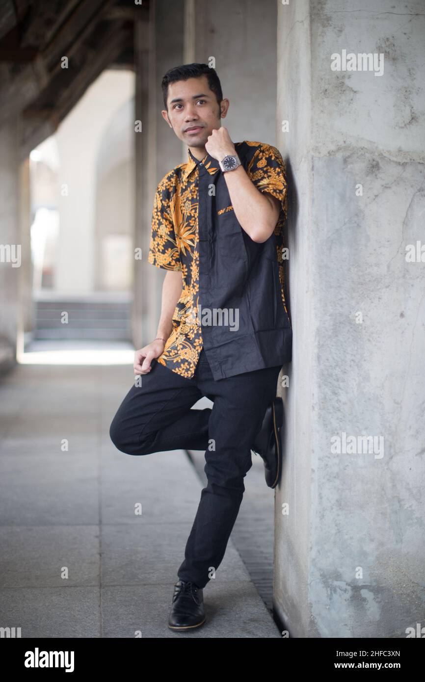 A young male model dressed in Indonesian Batik is posing among rows of ...