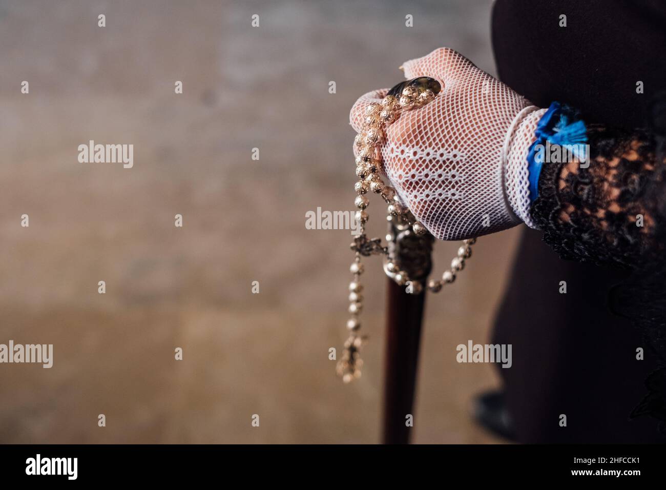 Woman dressed in traditional Andalusian Easter costume holds a rosary ...