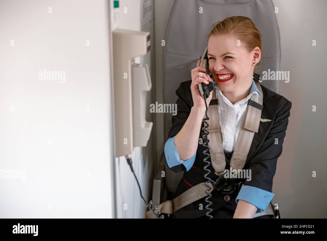 Joyful stewardess talking on telephone in airplane cabin Stock Photo ...