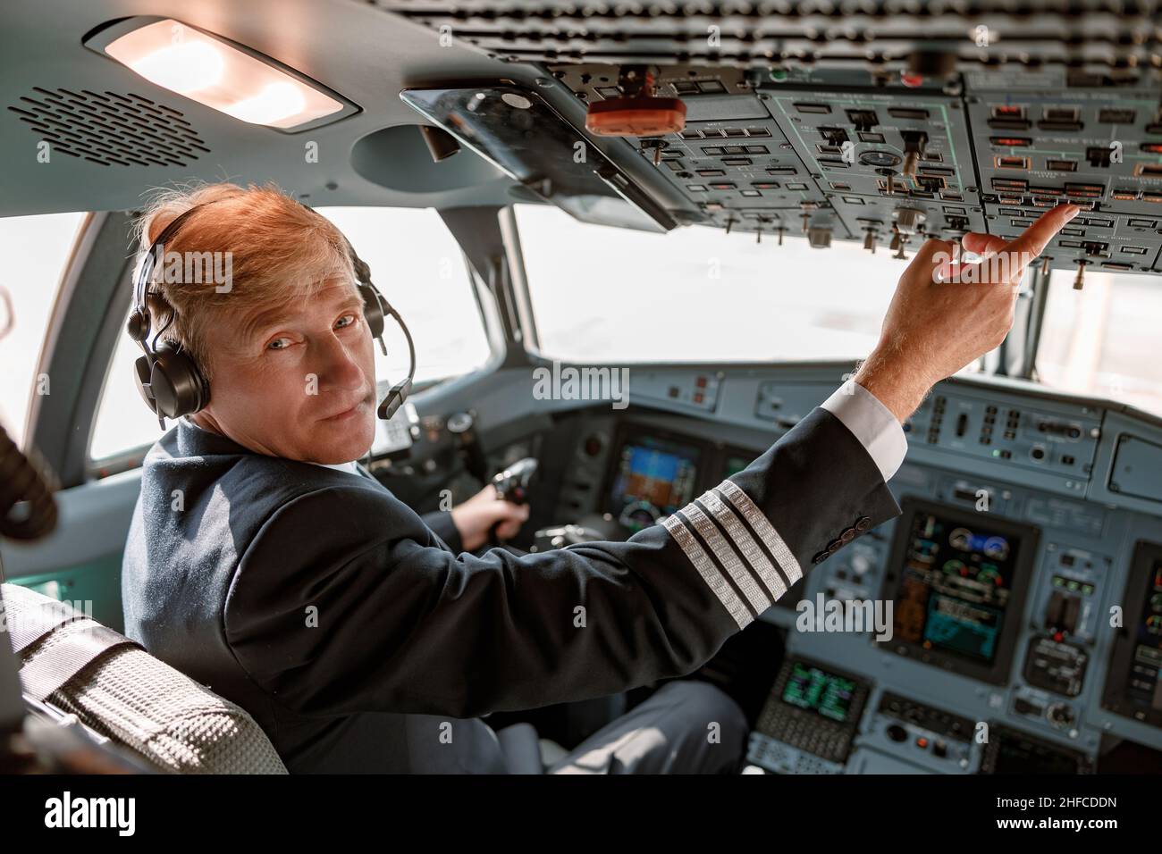 Male pilot pressing button on overhead panel in aircraft cockpit Stock ...