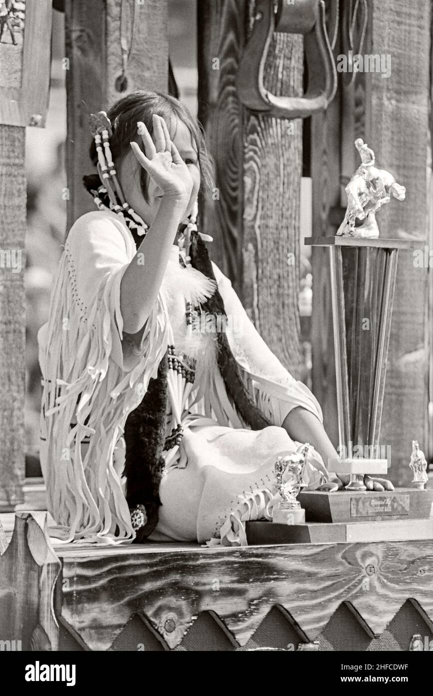 A young First Nations girl with a rodeo trophy waving her hand at the ...