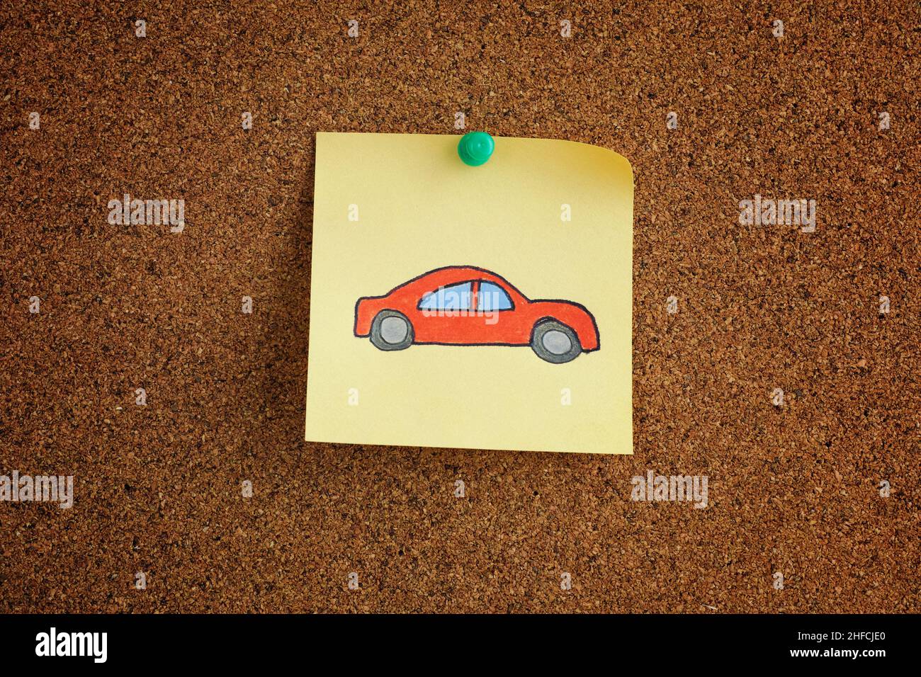 A sticky note with a drawing of a car on it pinned to a bulletin board ...