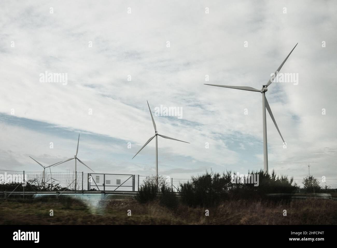 This photo shows wind turbines, standing in the middle of farmland ...