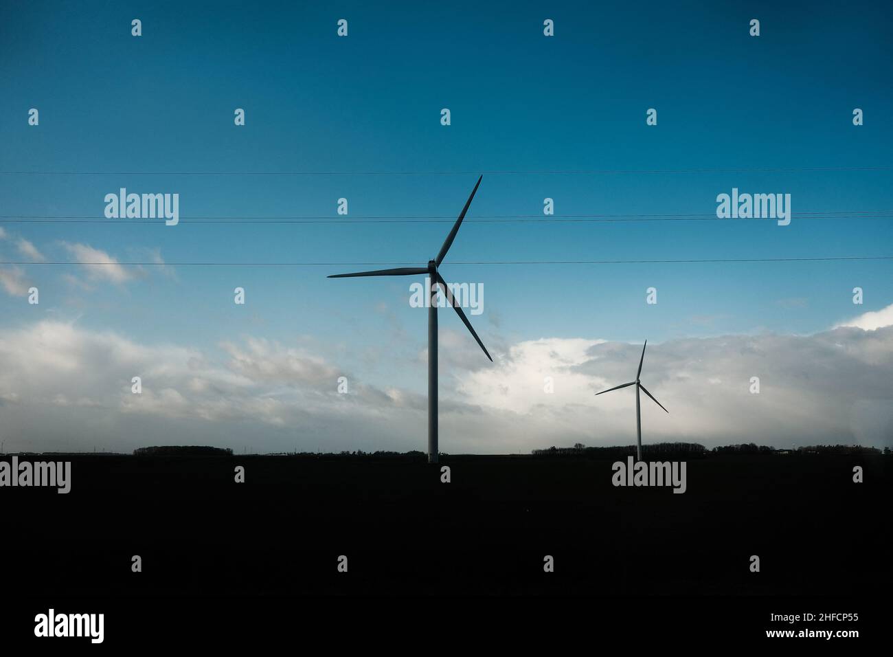 This photo shows wind turbines, standing in the middle of farmland ...