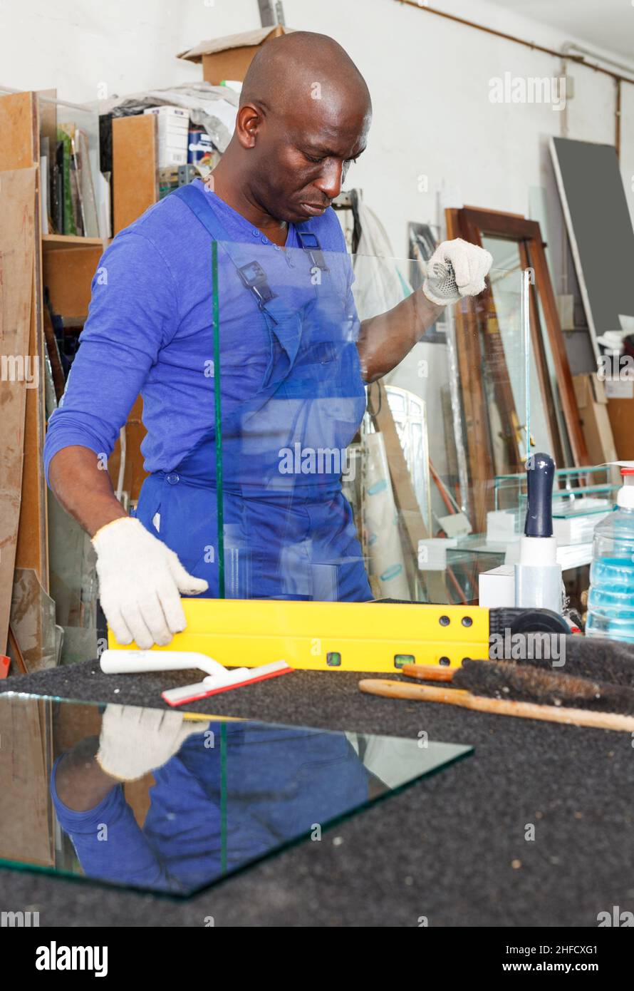glass factory worker measuring glass with angle finder level before ...