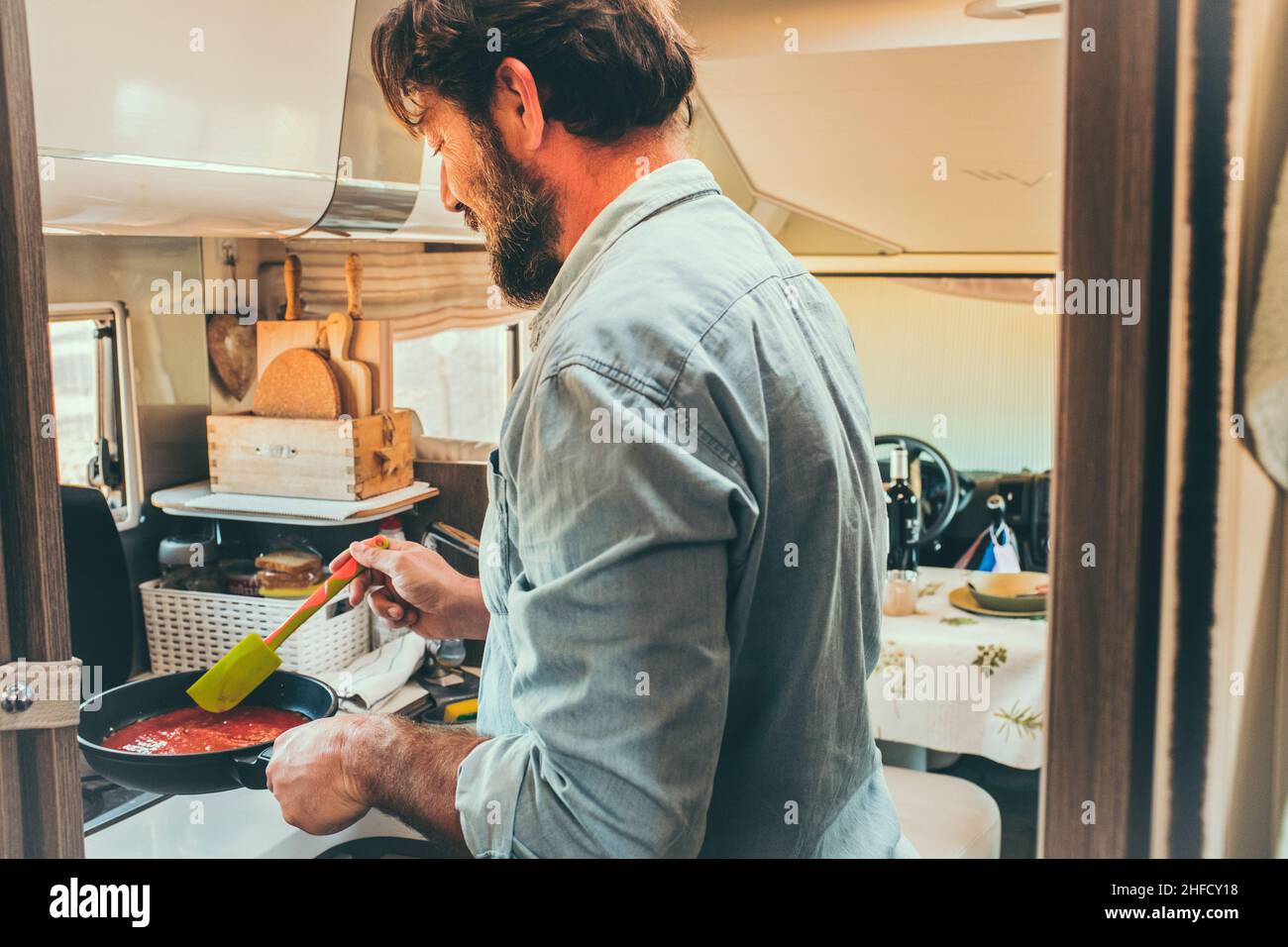 Man cooking in a camper van kitchen inside. Holiday travel vacation ...