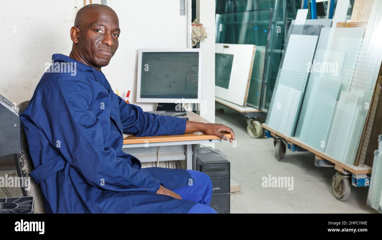professional glass factory worker sitting at workplace with computer ...