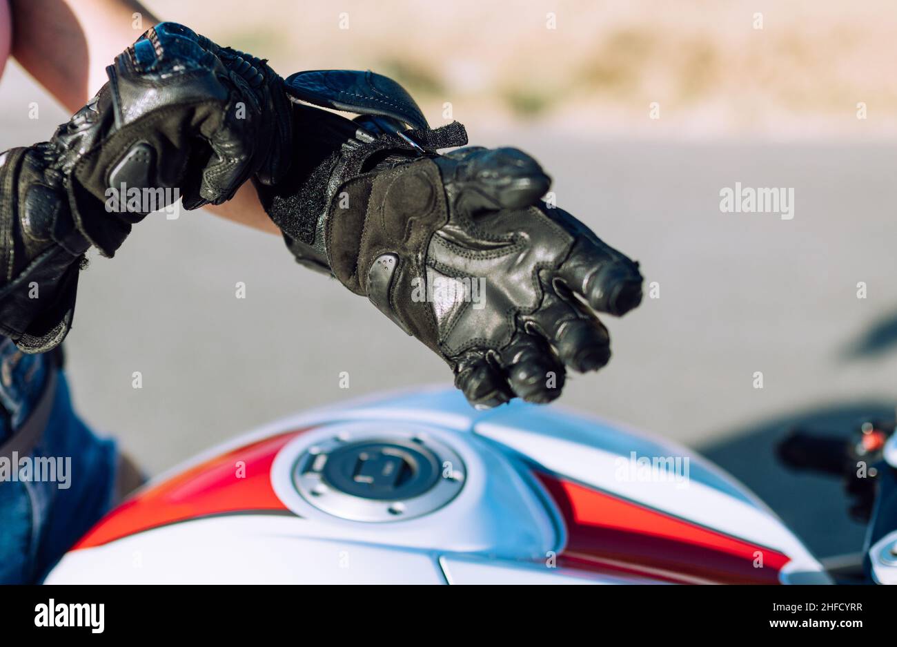 detail of the hand of a young biker woman putting on her leather ...