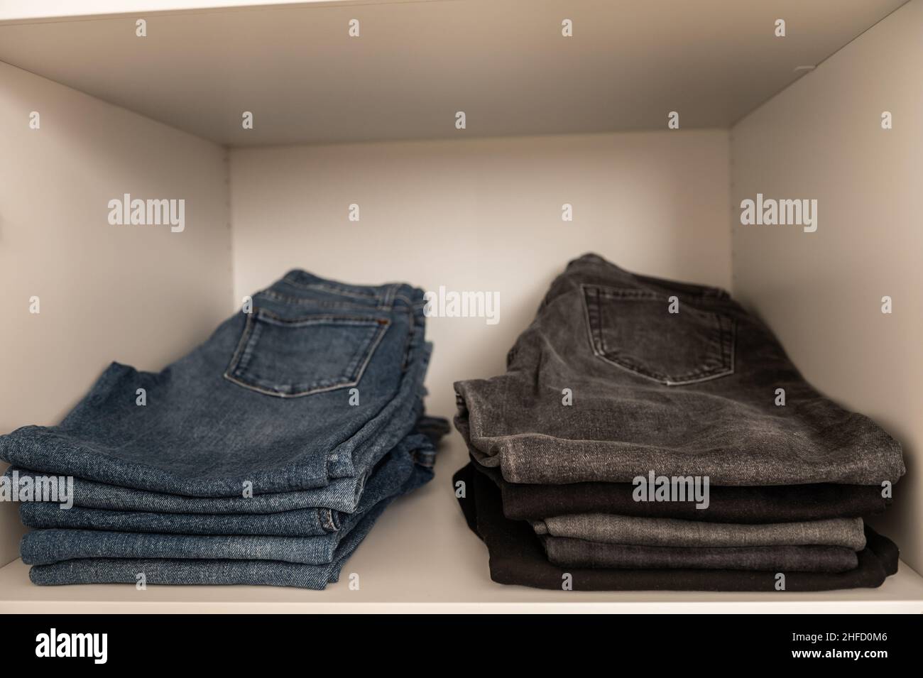 Closeup photo of pile of neatly folded blue jeans on shelf in wardrobe ...