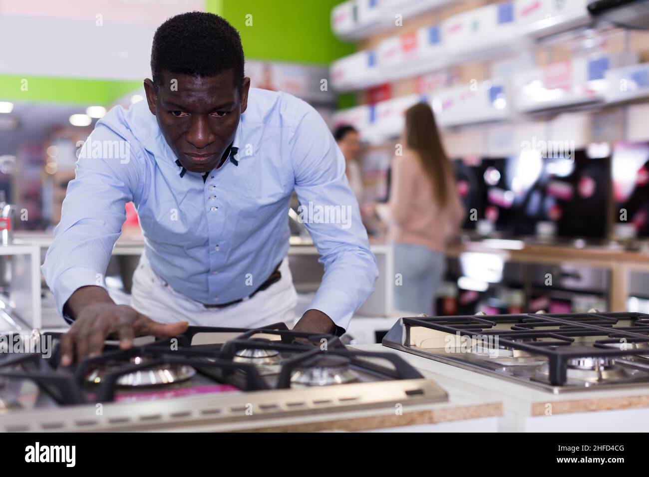 Happy male selecting new cooking top in store Stock Photo - Alamy