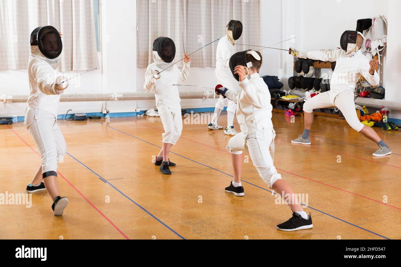 Adults and teens wearing fencing uniform practicing with foil Stock ...