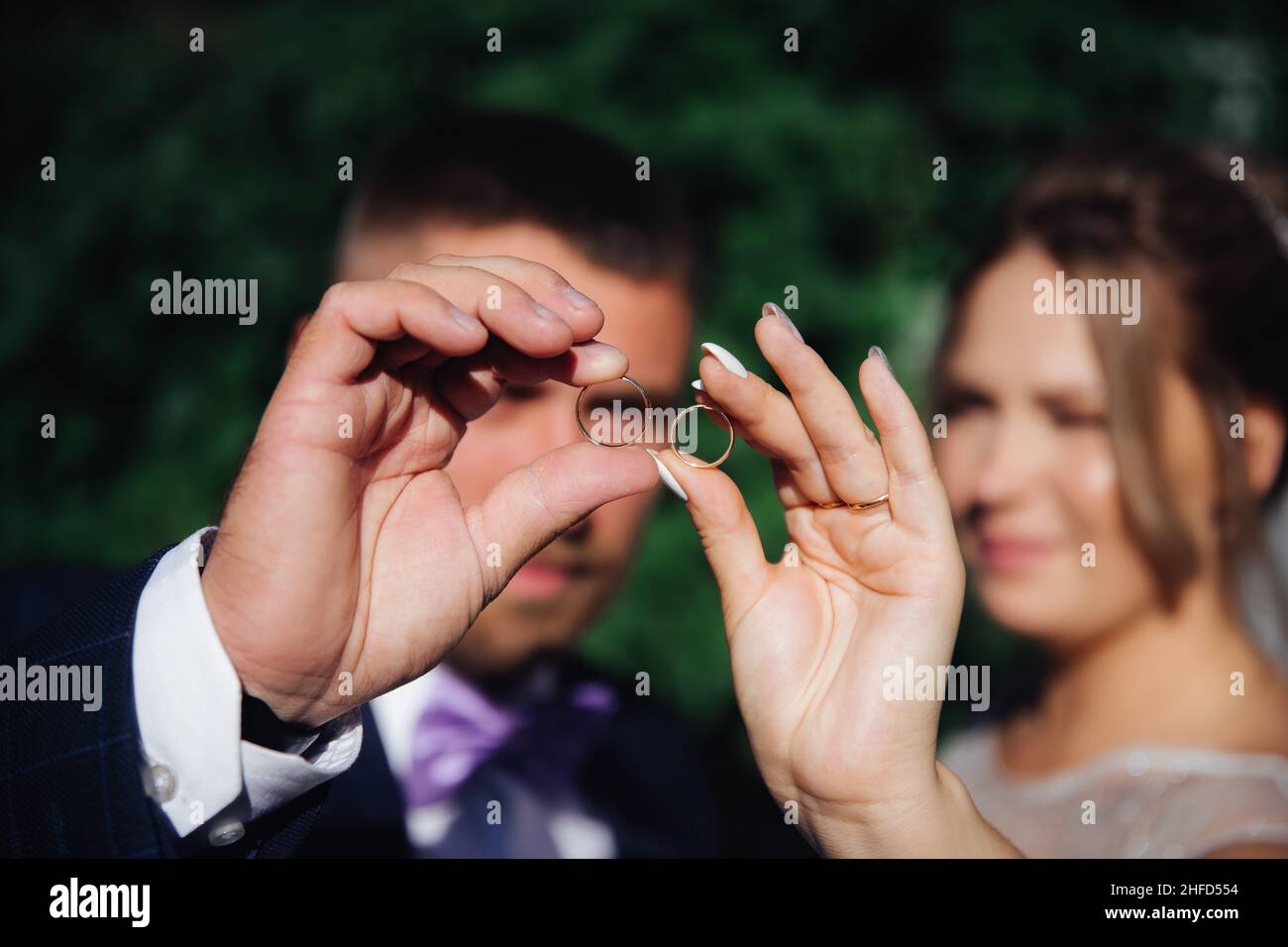 newlyweds look at wedding rings at a shallow depth of field on a clear ...