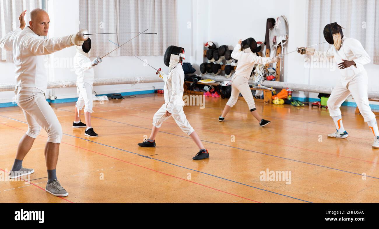 Coaches demonstrating to young athletes attack movements with rapier ...