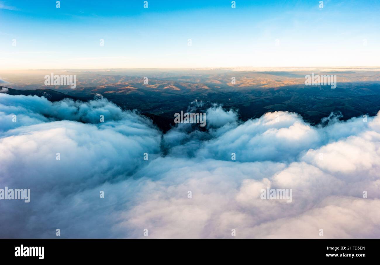 Blue sky above thick layer of white fluffy clouds at bright orange ...
