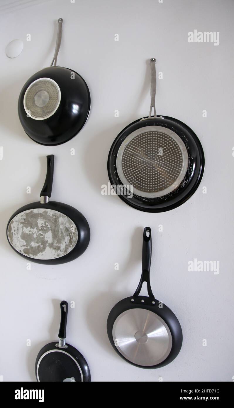 Pans in different sizes are hung on the kitchen wall. Pans have been ...