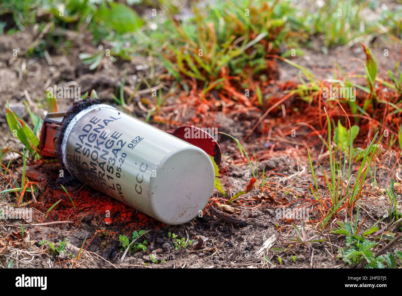 a discharged British Army red smoke grenade lying on mud and grass ...