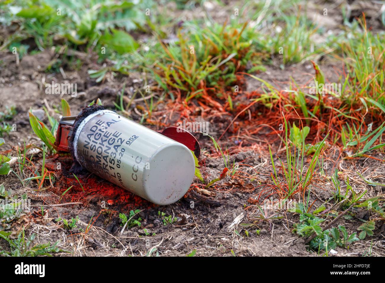 a discharged British Army red smoke grenade lying on mud and grass ...