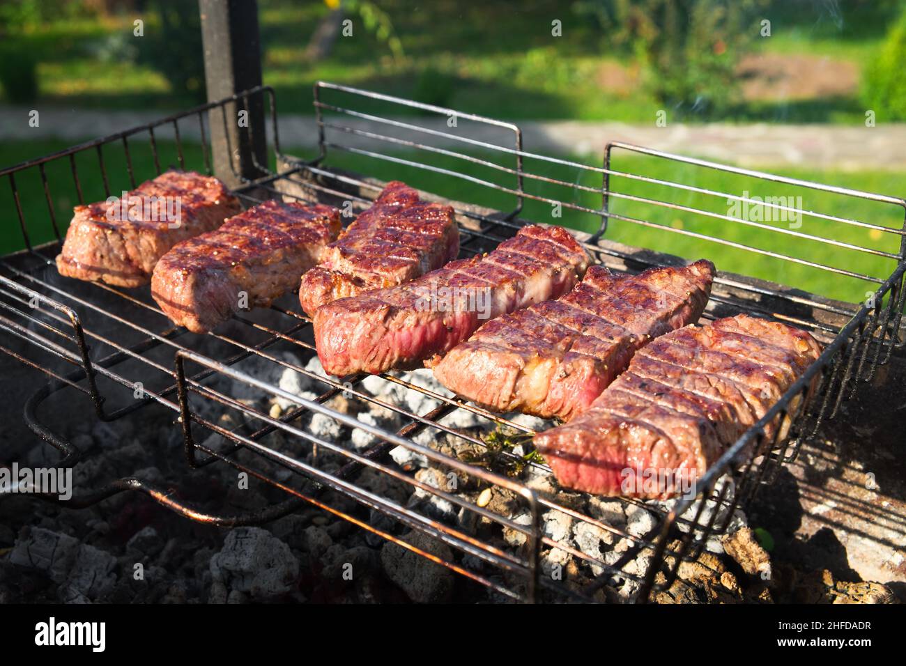 Grilled meat on a wire rack. Steaks barbecue on a brazier with natural ...