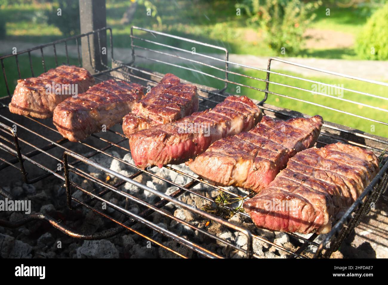 Closeup photo of medium grilled meat on a wire rack. Steaks barbecue on ...