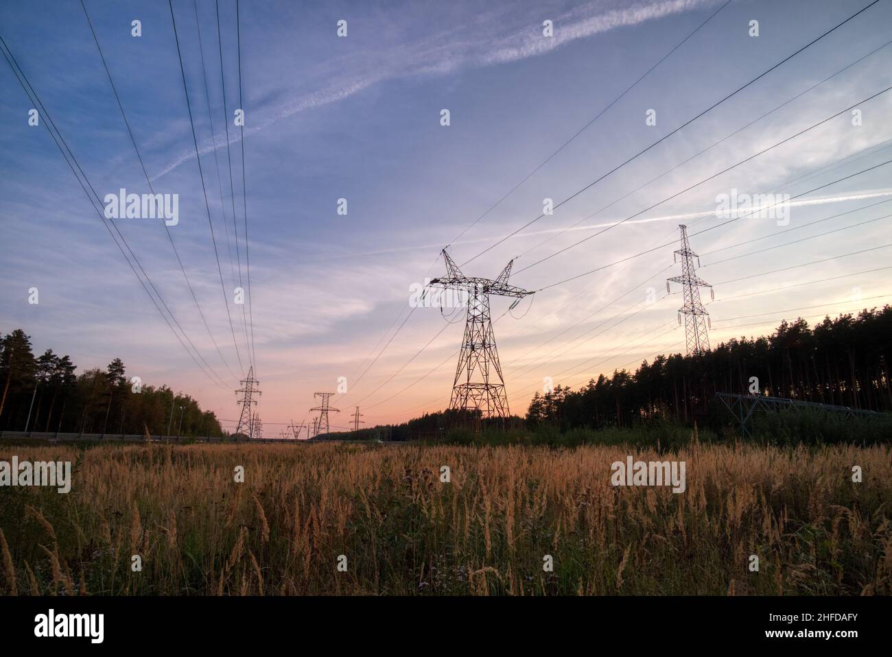 Power line supports at the evening sunset. Electricity pylons at orange ...