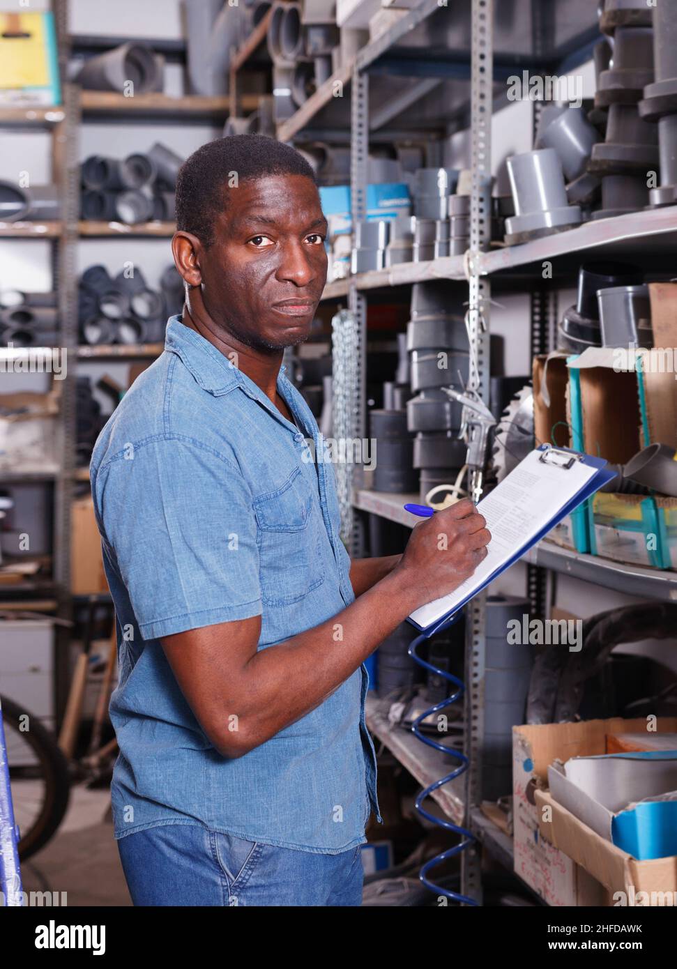 African American salesman checking goods availability on shelves of ...
