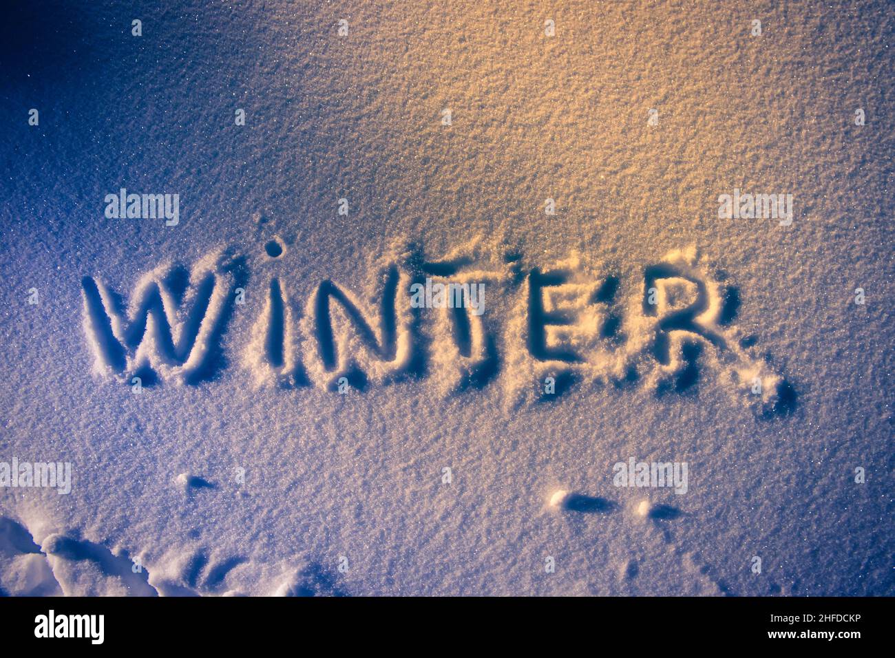 Text winter on snow surface in cold night time lighten by warm orange ...