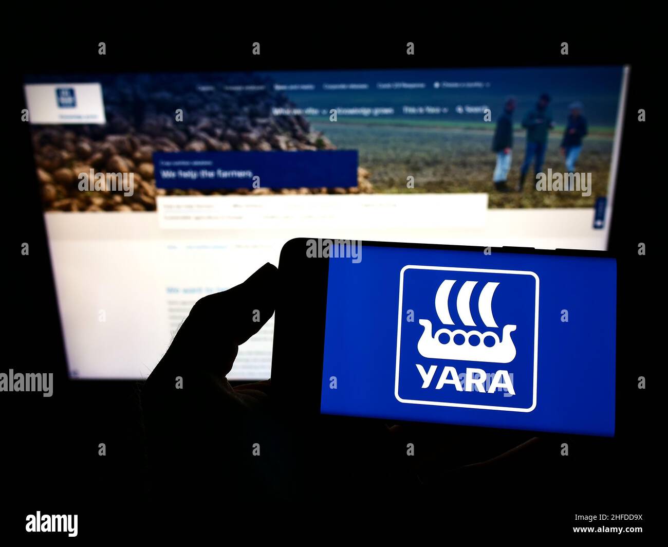 Person holding cellphone with logo of Norwegian chemical company Yara International ASA on ...