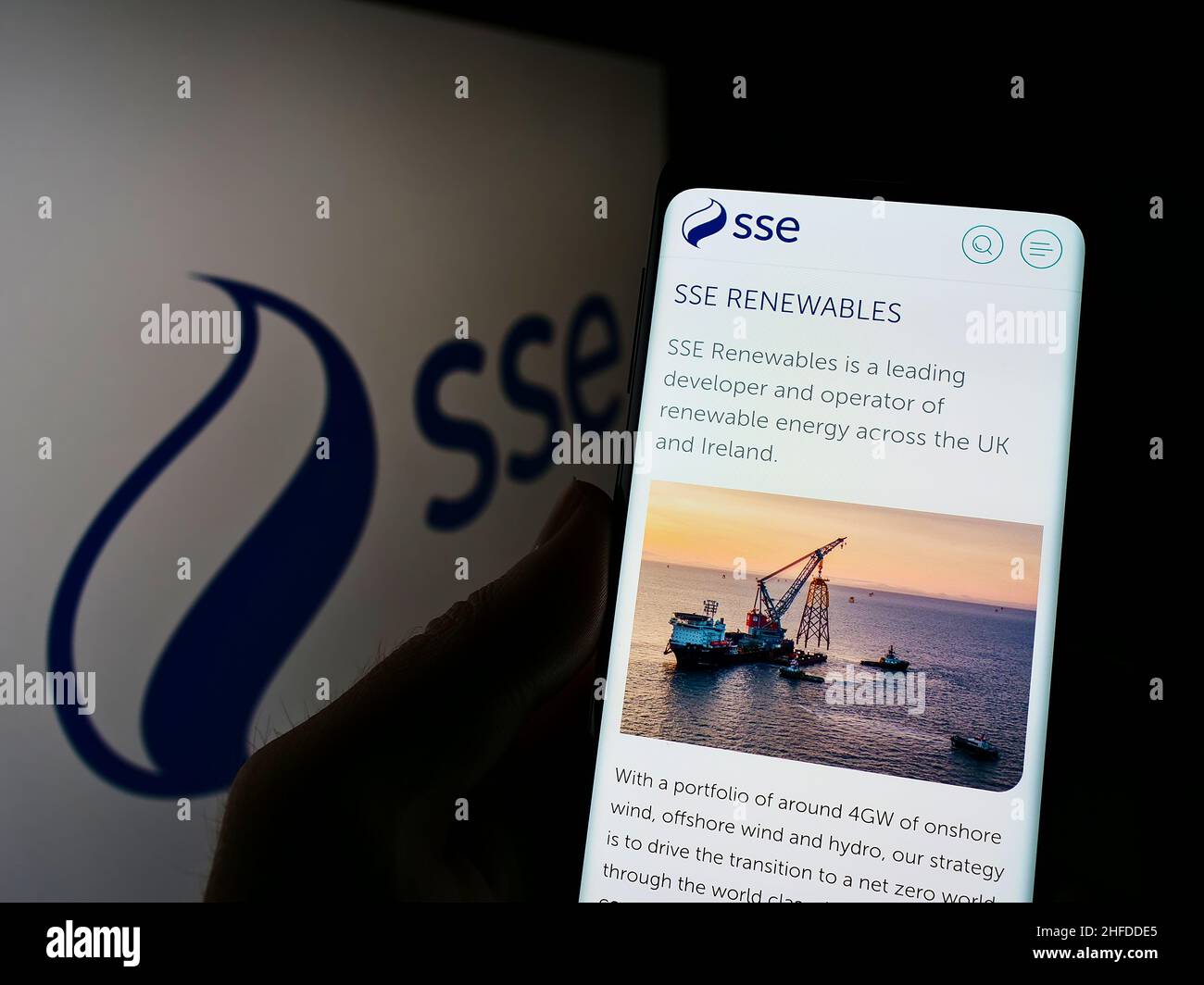 Person holding cellphone with webpage of British energy company SSE plc ...