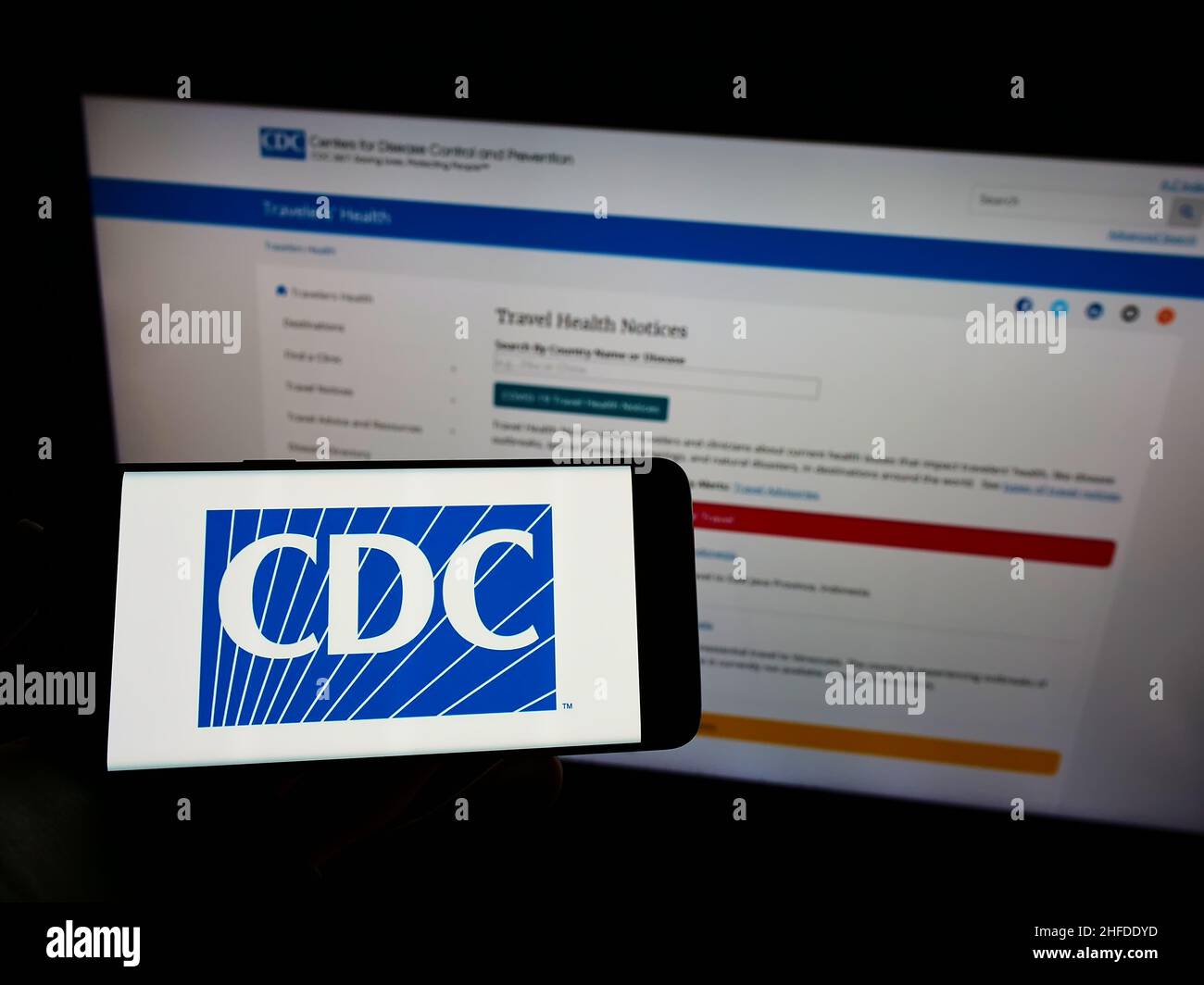 Person holding mobile phone with logo of Centers for Disease Control ...