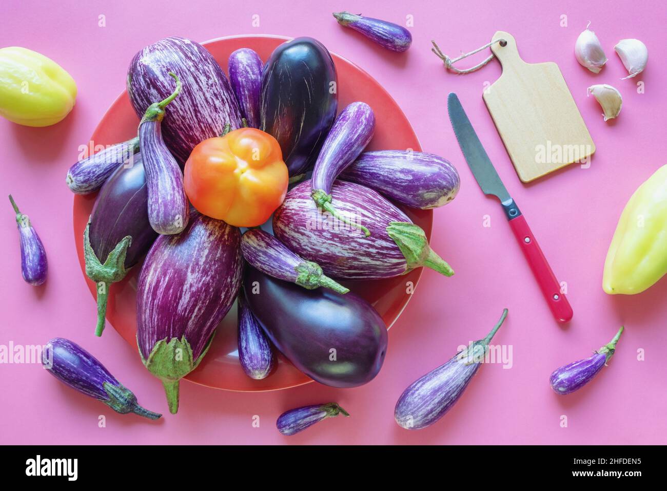 Vegetables. Bell peppers and eggplants in red plate on pink background ...