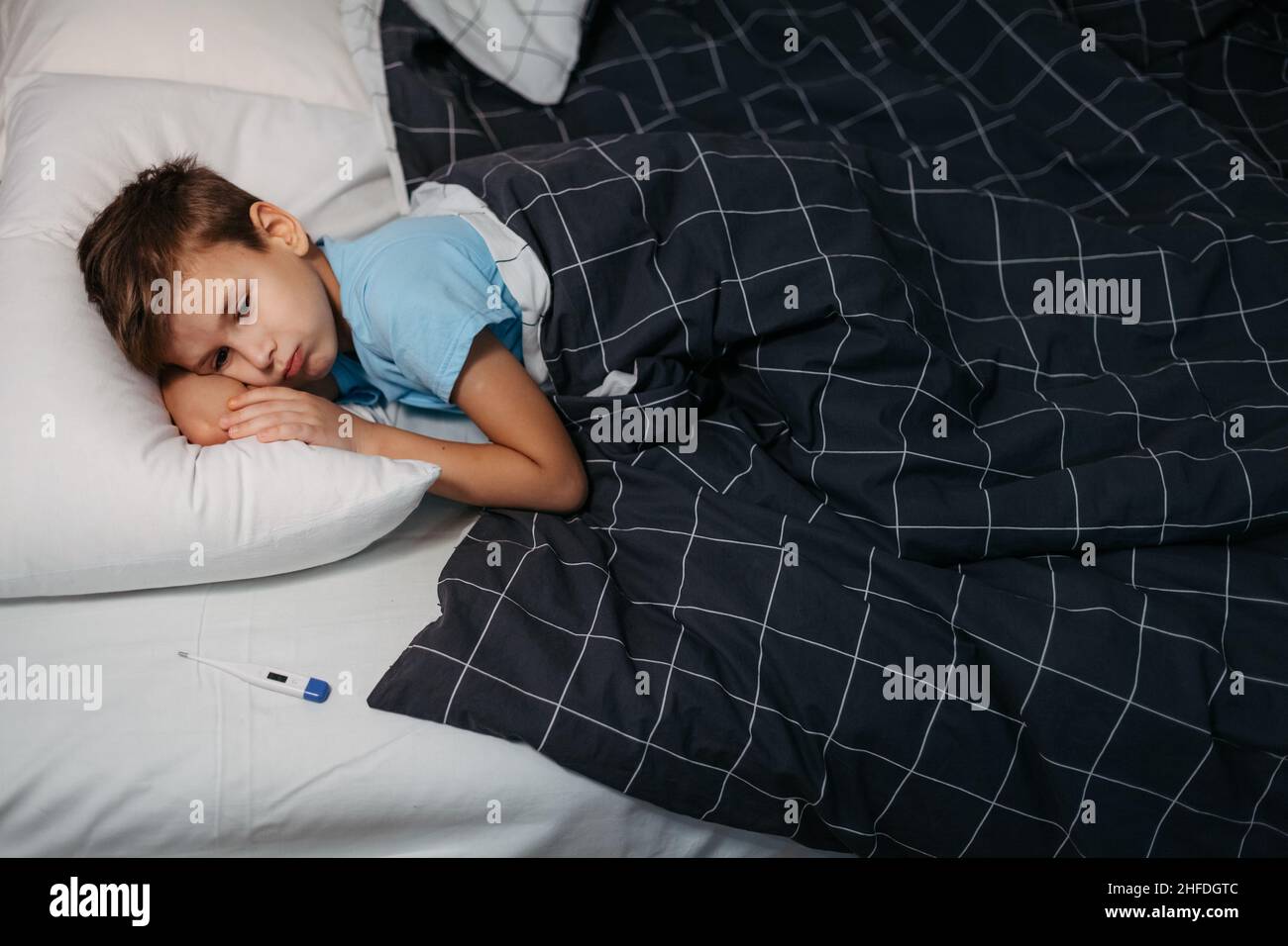 Sick child laying in bed and looking very sad Stock Photo - Alamy