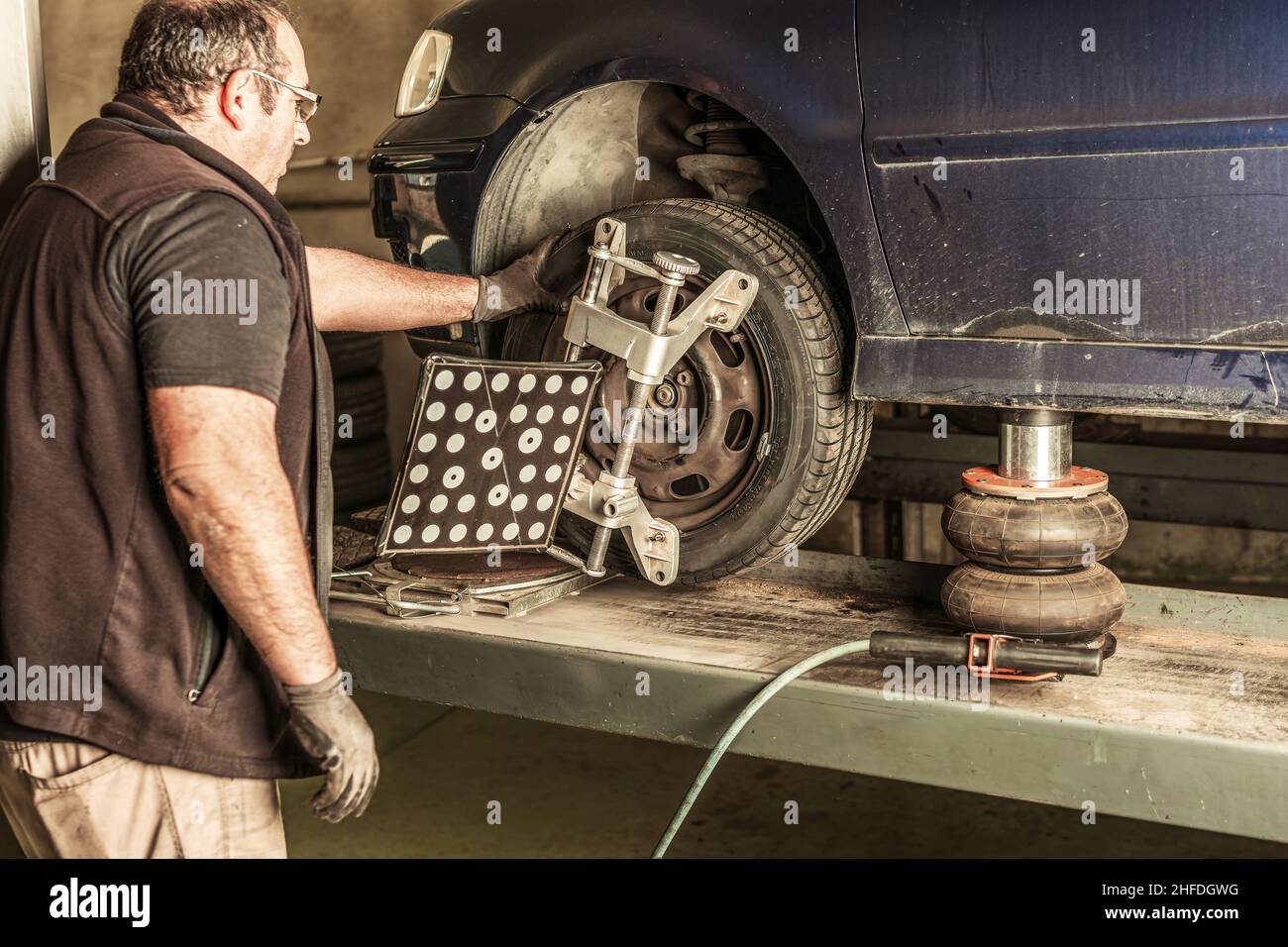 Mechanic checking the operation of a pneumatic jack under a car to lift ...