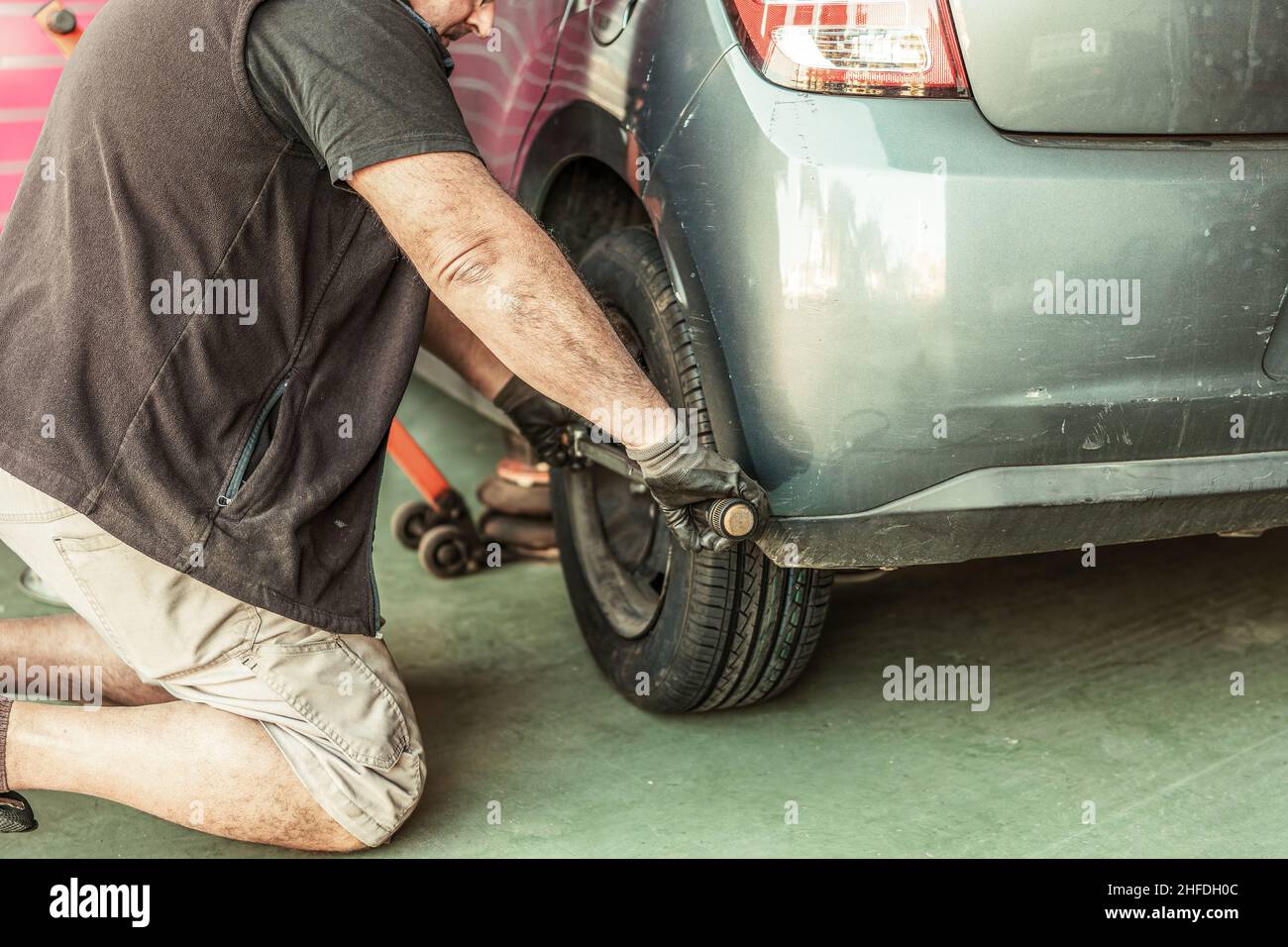 Mechanic fitting the wheel on a car in a workshop Stock Photo - Alamy