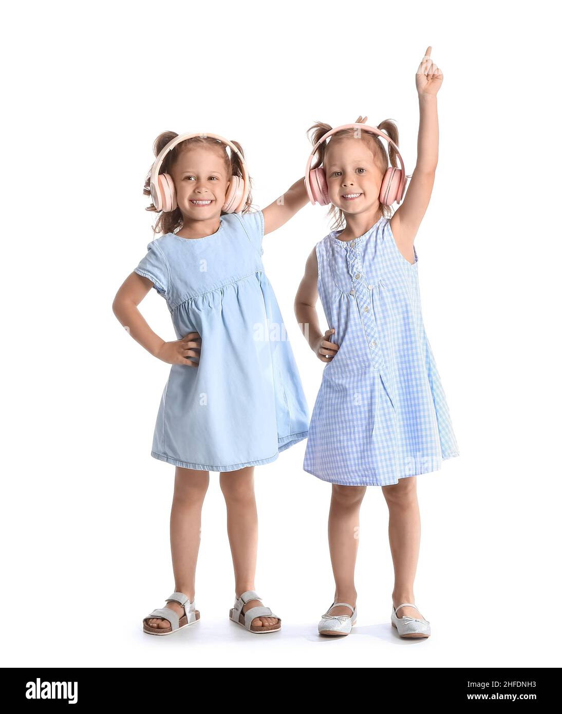 Adorable little sisters in headphones dancing on white background Stock ...