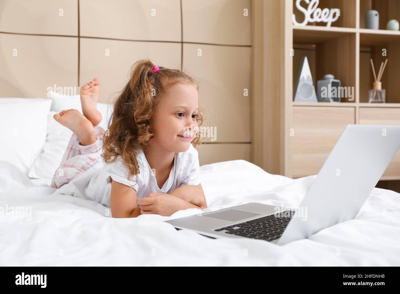 Adorable little girl with laptop lying on bed at home Stock Photo - Alamy