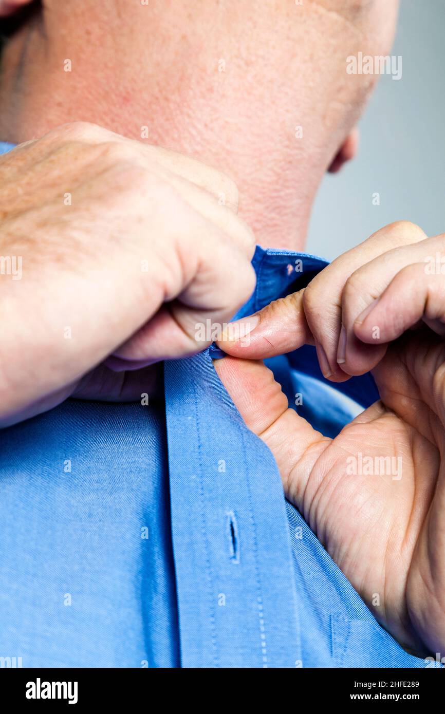 Young man buttoning-up white shirt Stock Photo - Alamy