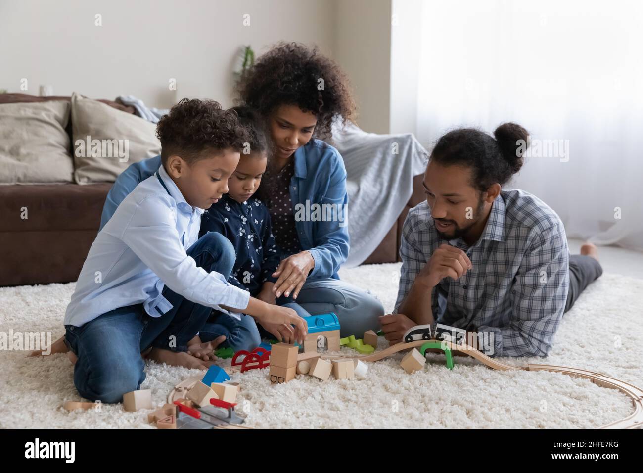 Happy young parents and two kids constructing building wooden blocks ...