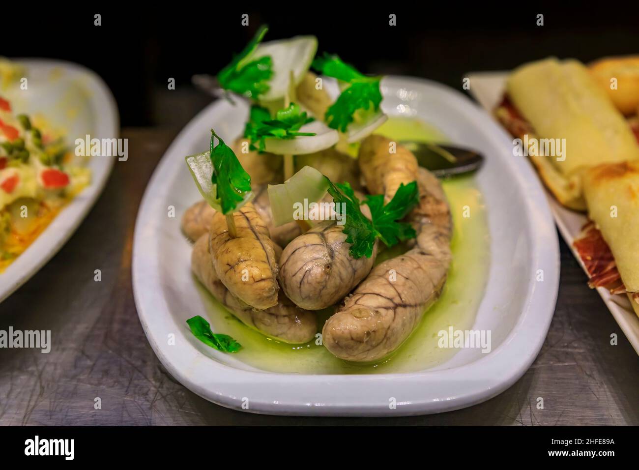 Traditional Spanish pintxos of sausage in natural casing on display in ...