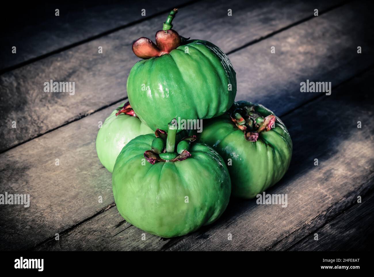 Still life with fresh garcinia cambogia on wooden background. Garcinia is thai herb (south of ...