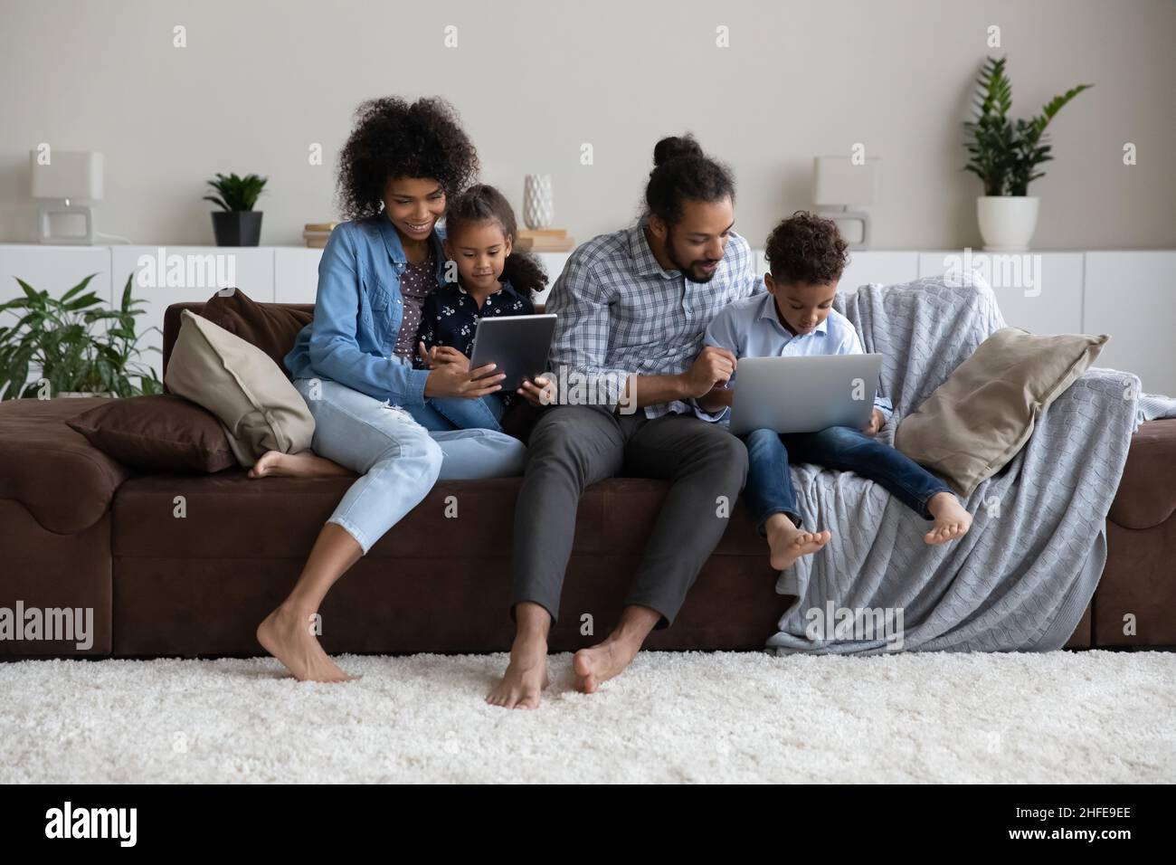 Happy African parents and gen Z kids sitting on couch Stock Photo - Alamy